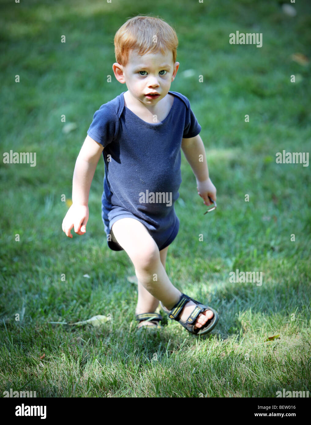 Boy walking outside on grass Stock Photo - Alamy