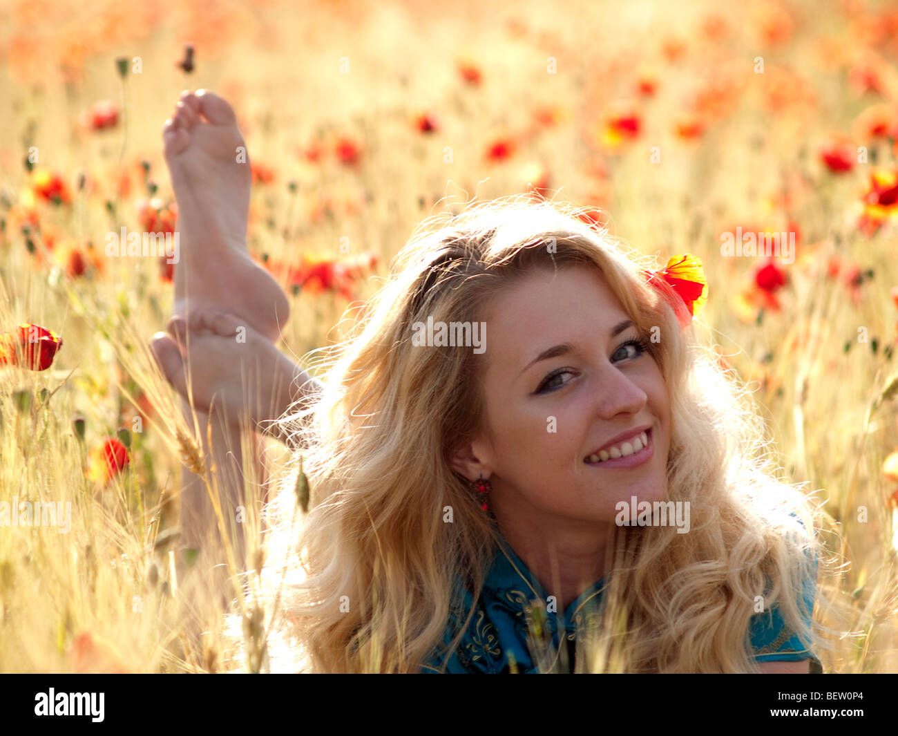Beautiful Barefoot blond lady laying in poppy field Stock Photo - Alamy