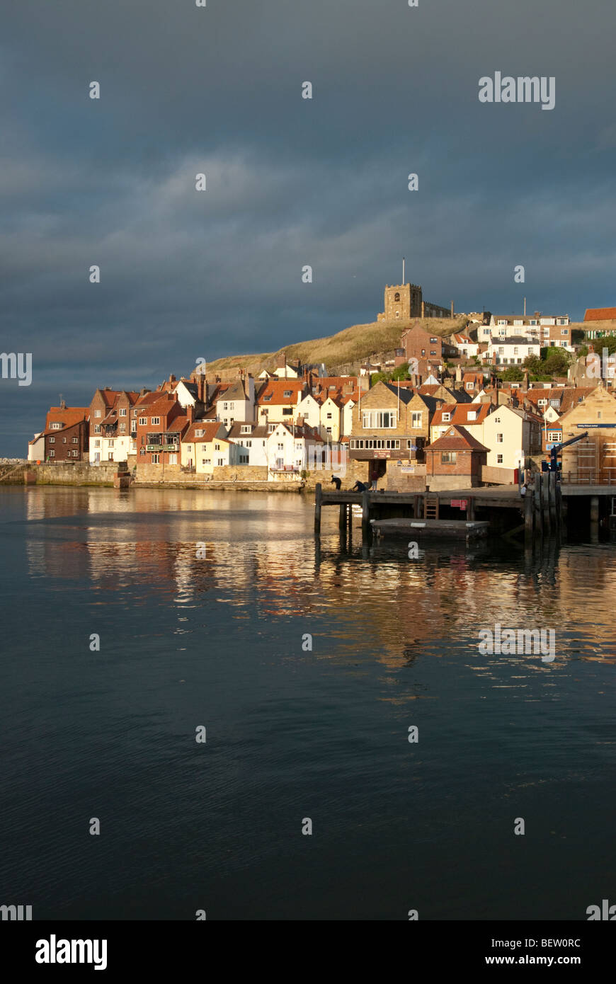 Evening light illuminates Whitby harbour and St Mary's Church at dusk ...