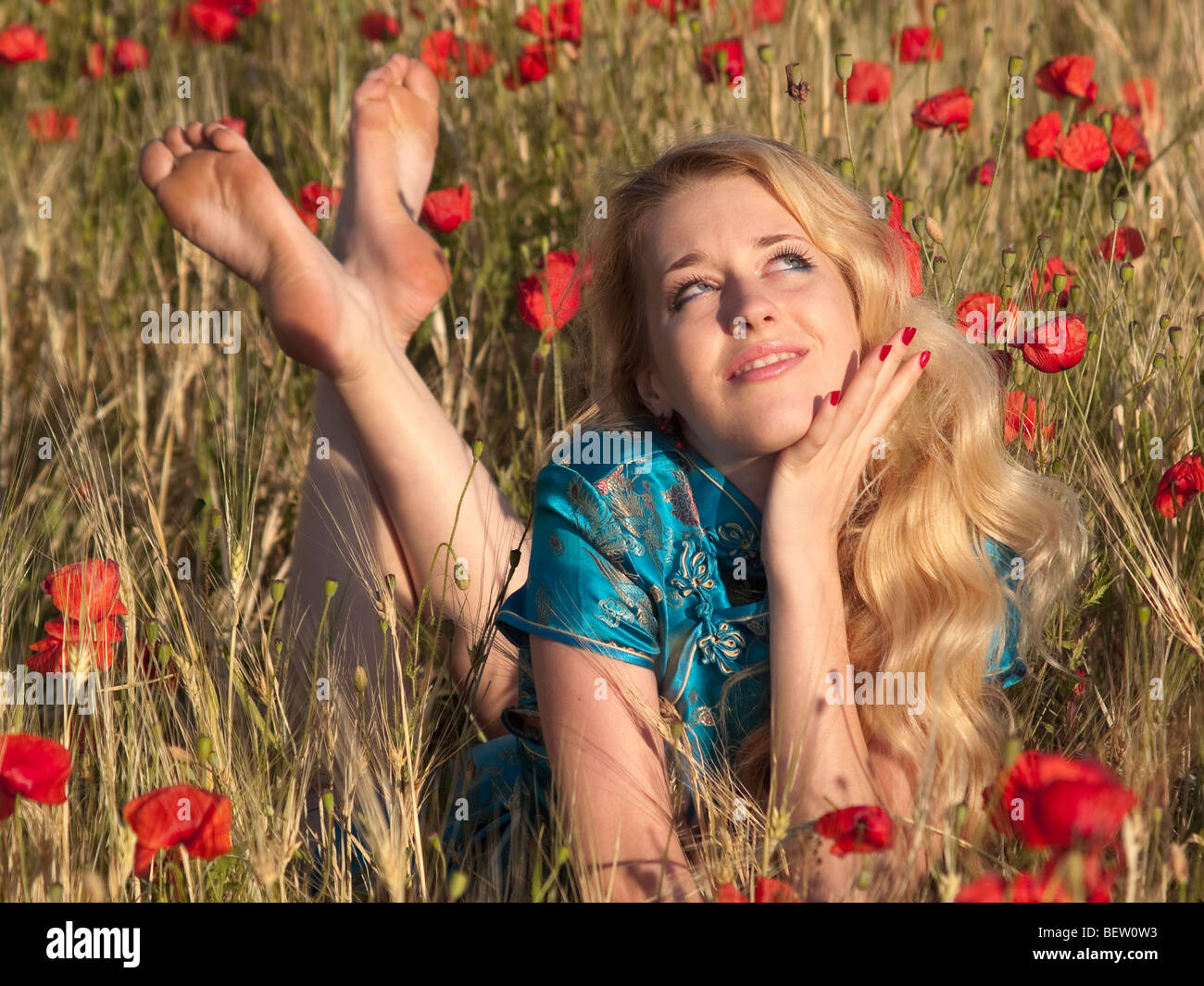Beautiful Barefoot blond lady laying in poppy field Stock Photo - Alamy