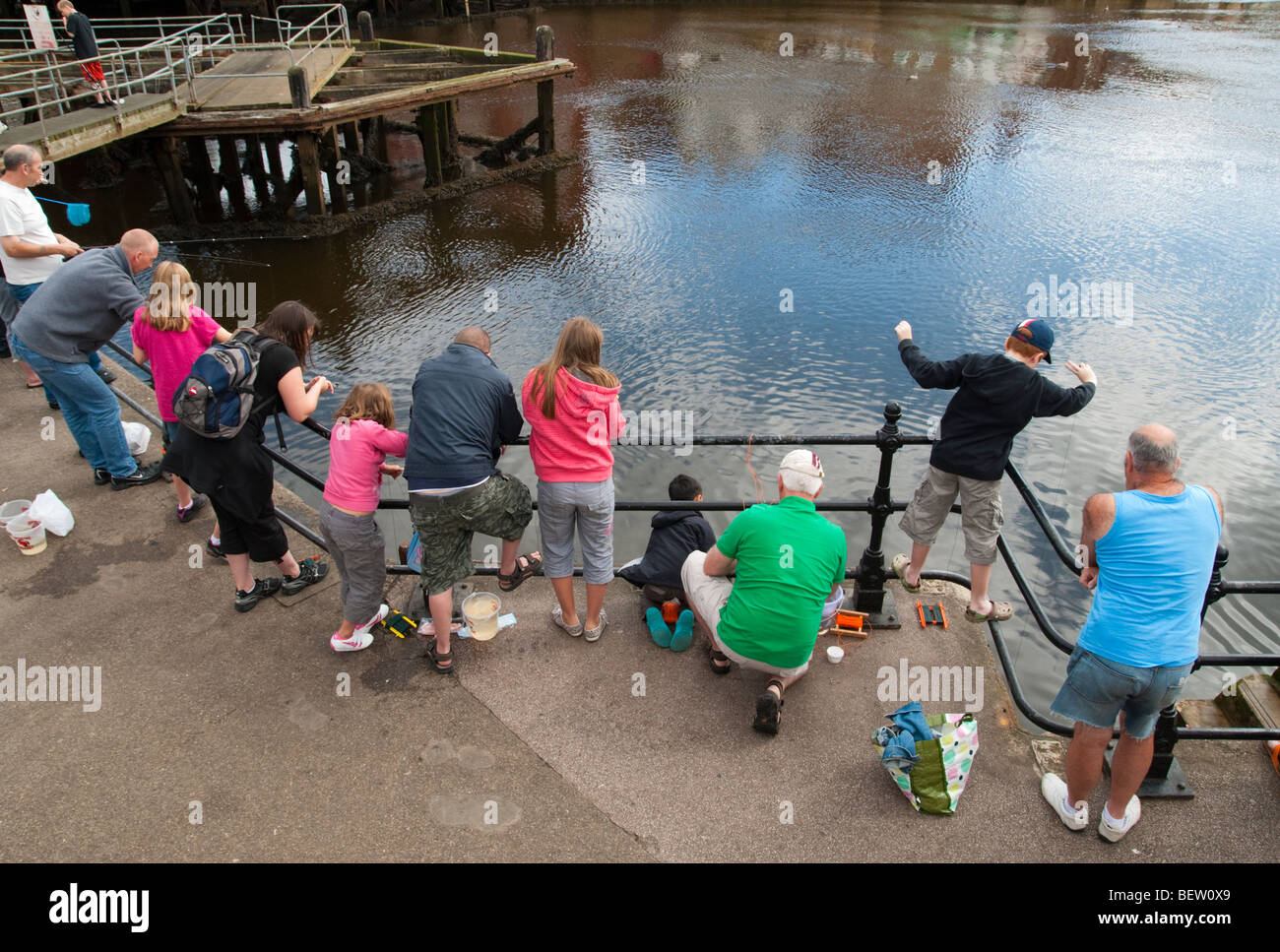 Visitors to Whitby fish for crabs over the railing along the harbour's ...
