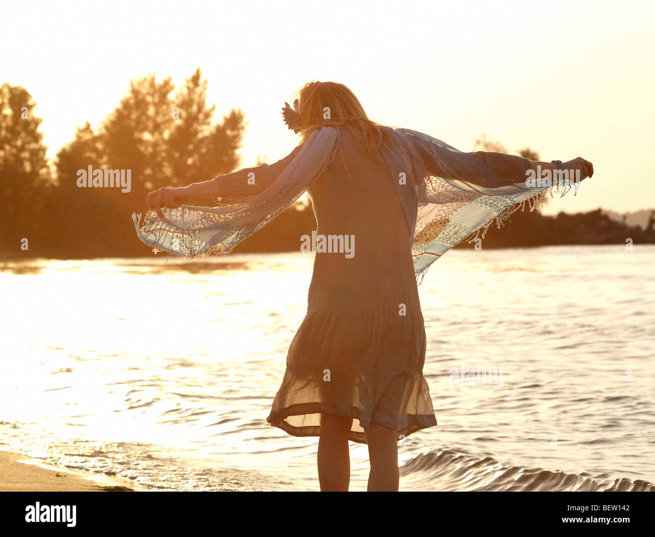 Blond beautiful lady with fabric on shore in sunset Stock Photo - Alamy