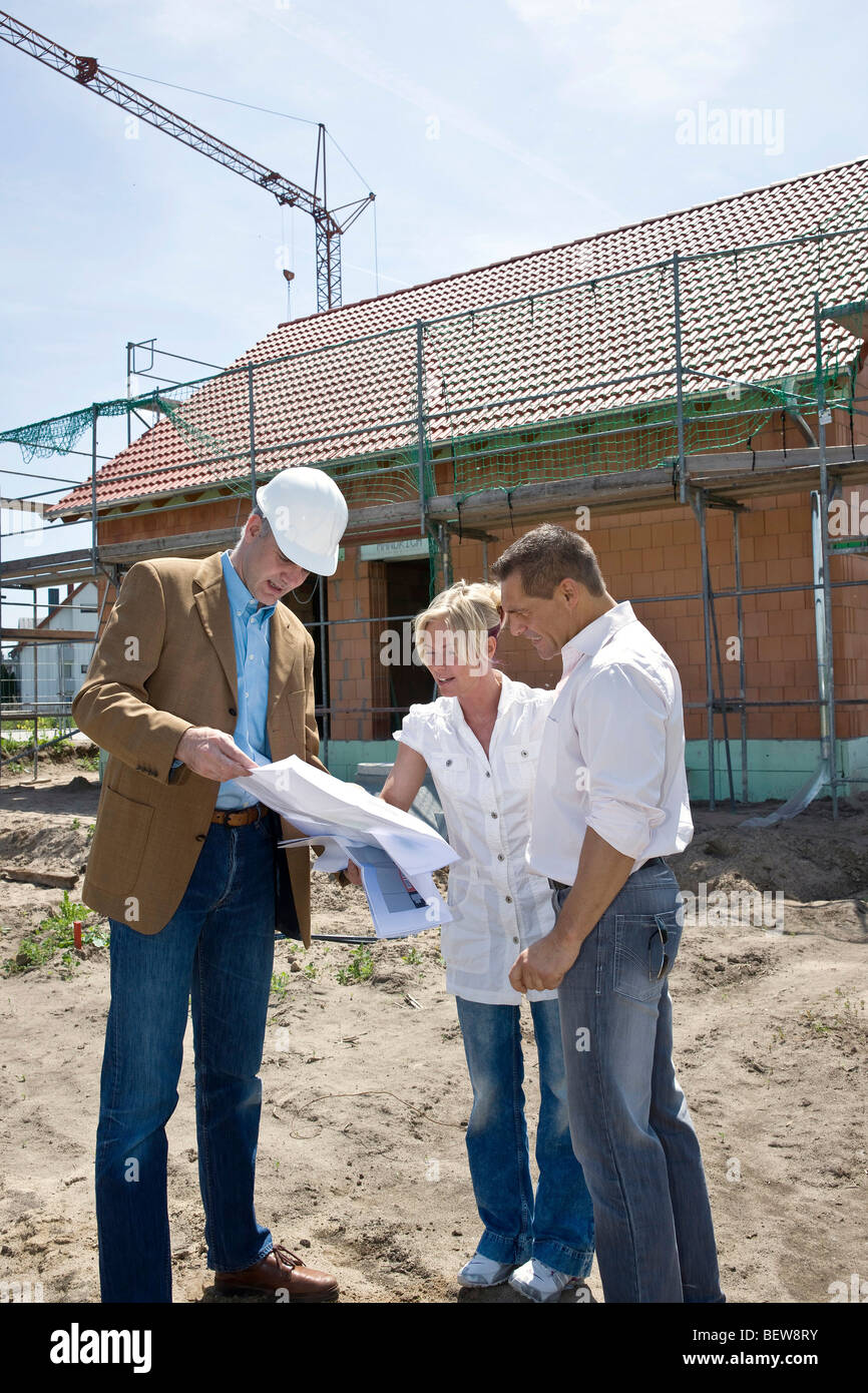 Couple talking architect at a construction site Stock Photo - Alamy