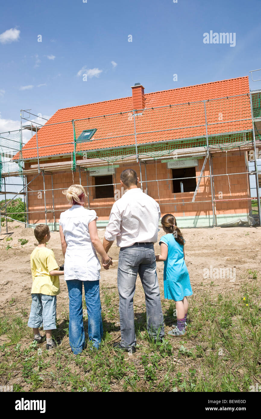 Family with two children looking at house under construction, rear view ...