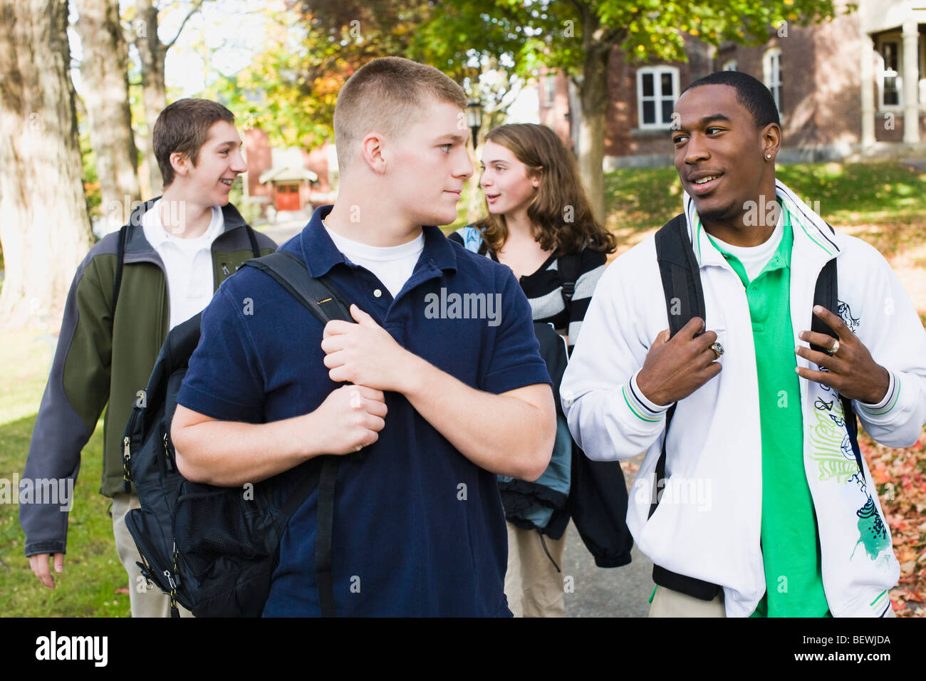 Four students walking together Stock Photo - Alamy