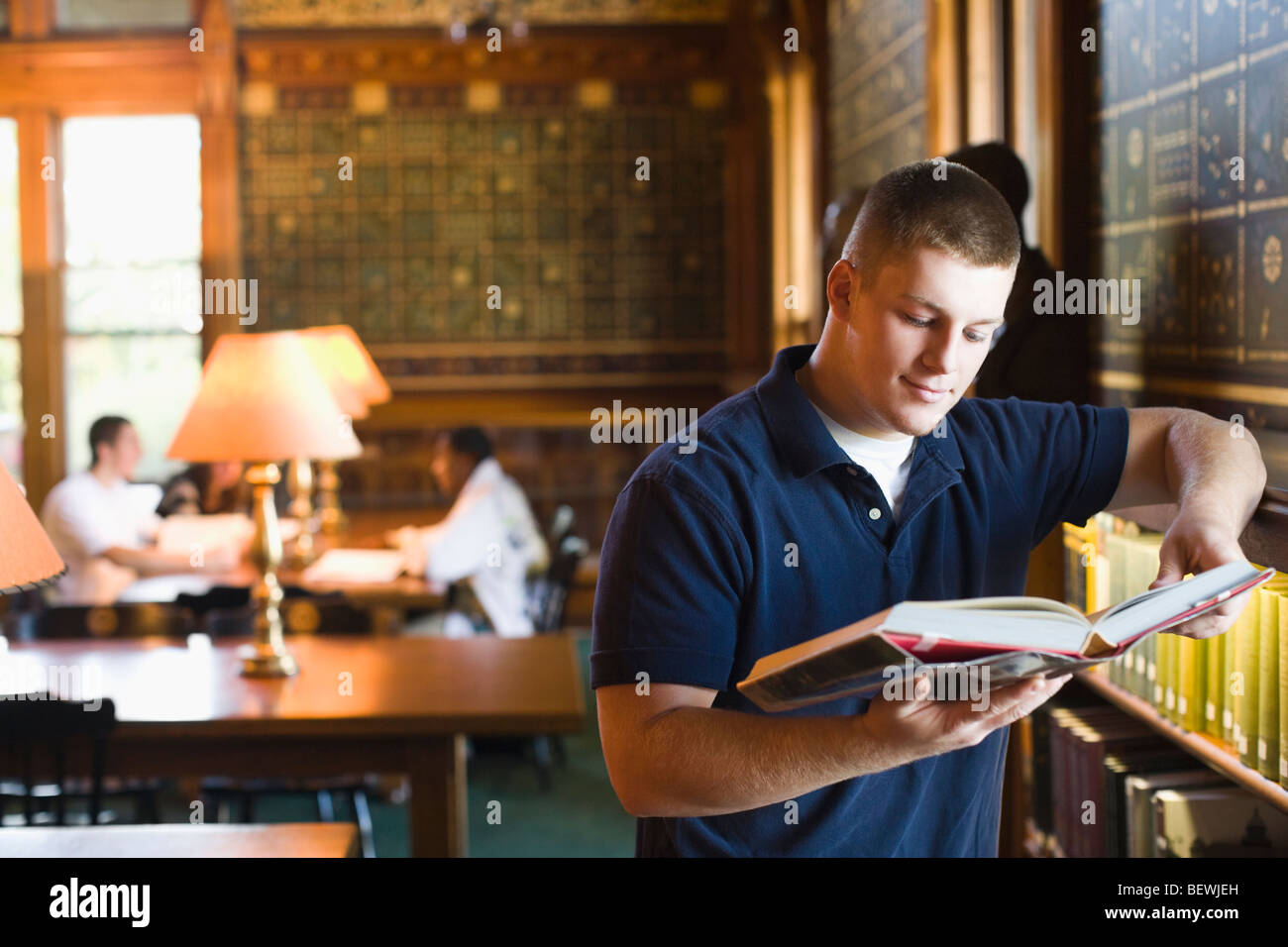 Student reading a book in a library Stock Photo - Alamy