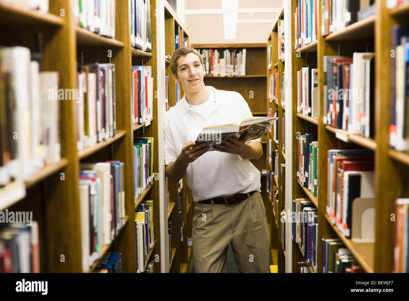 Student holding a book and standing in a library Stock Photo - Alamy