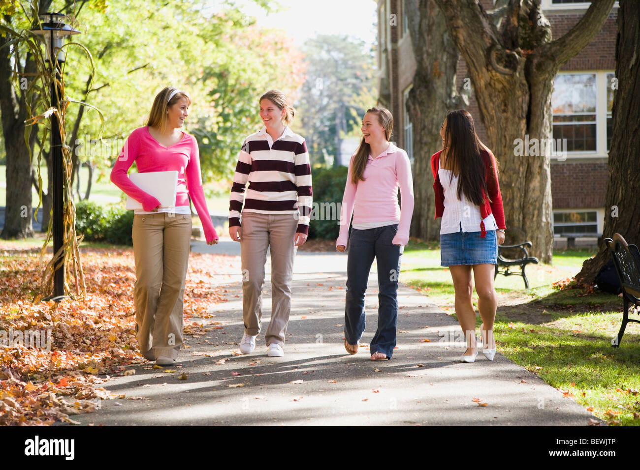 Four students walking together and smiling Stock Photo - Alamy