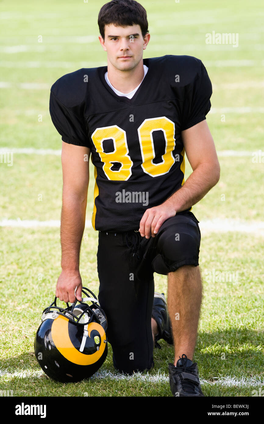 Portrait of a football player kneeling in a field Stock Photo - Alamy