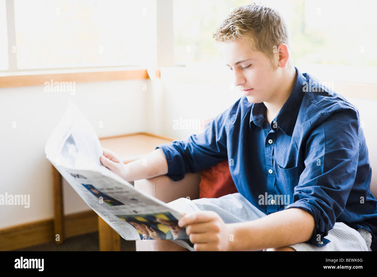 Teenage boy reading a newspaper Stock Photo - Alamy