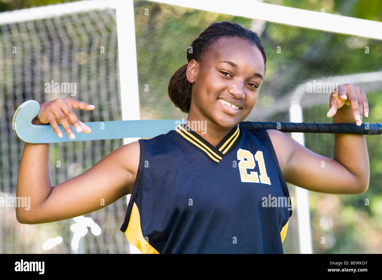 Female hockey player holding a hockey stick and smiling Stock Photo - Alamy