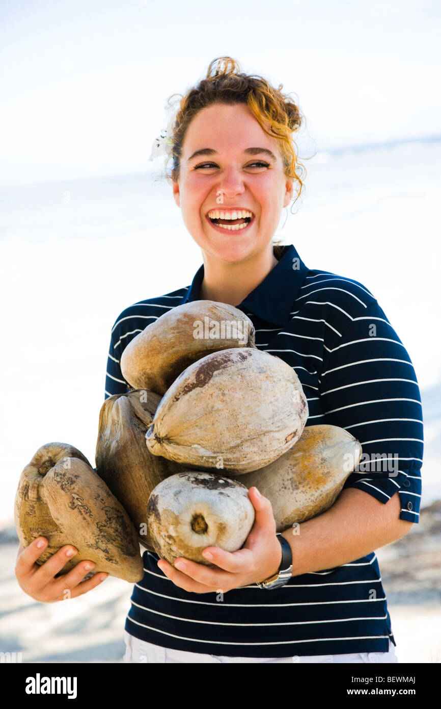 Woman holding coconuts and smiling on the beach, Tahaa, Tahiti, French ...