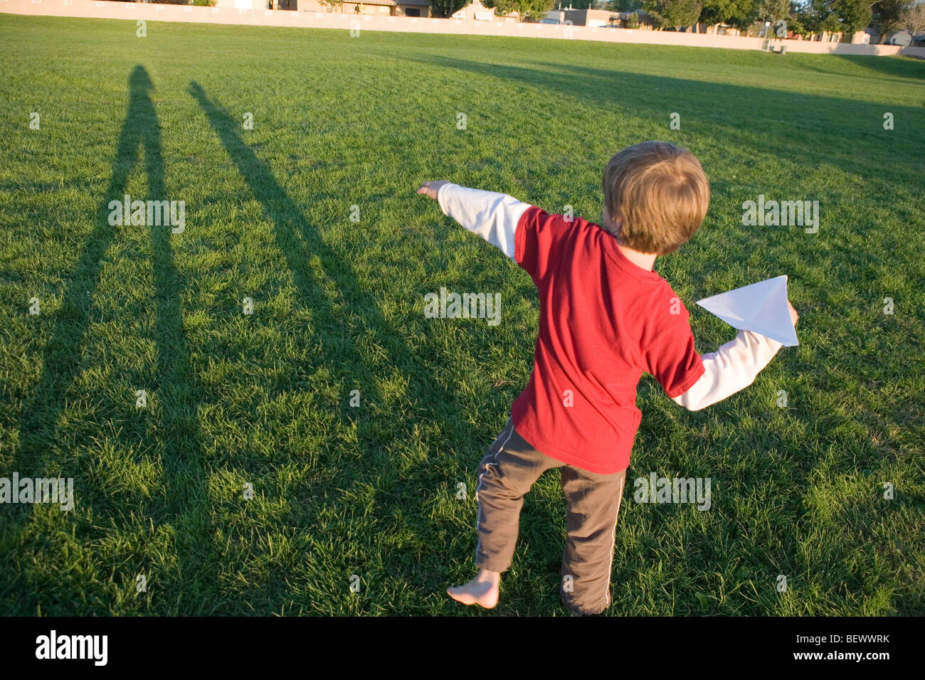 seven year old boy getting ready to throw his paper airplane in a park ...