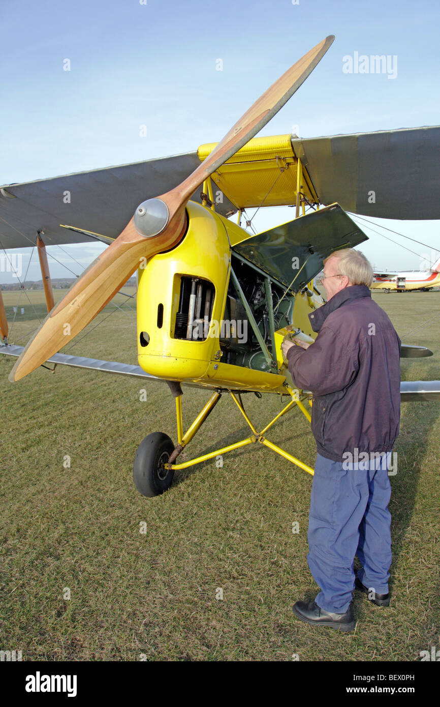 A bright yellow Tiger Moth bi-plane and pilot on an old airfield at ...