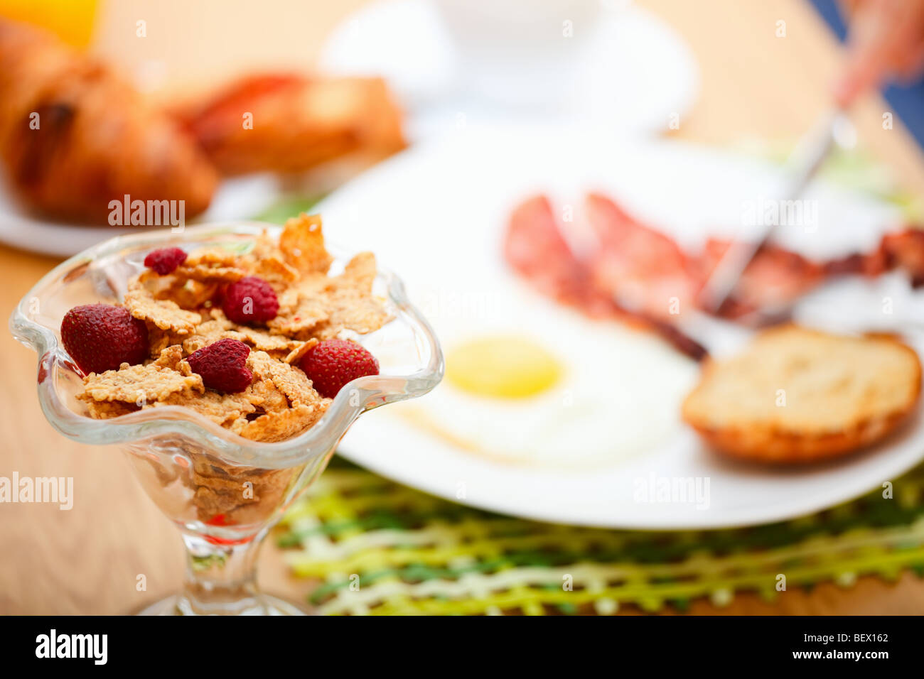 Delicious breakfast served. Corn flakes with berries, fried egg, bacon ...
