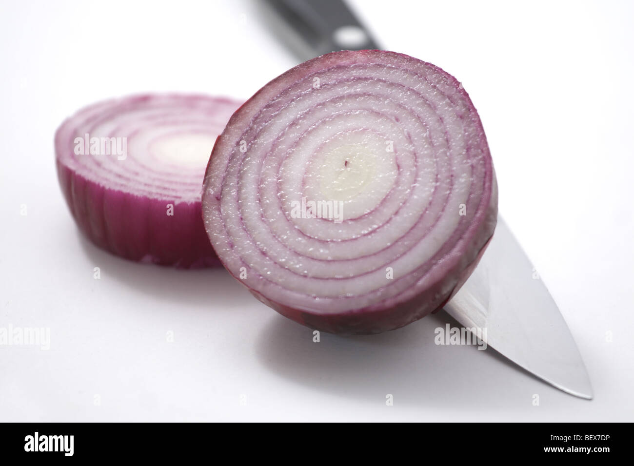 A red onion sliced in half on a white backgroundwith a knife Stock ...