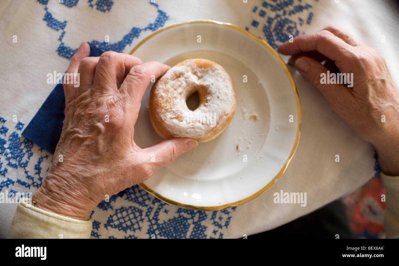 Senior eating a donut Stock Photo - Alamy