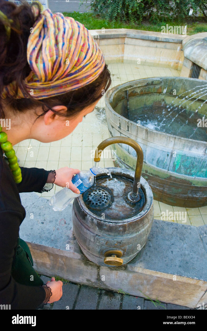 Person filling up her water bottle off a fountain in Sopron Hungary ...