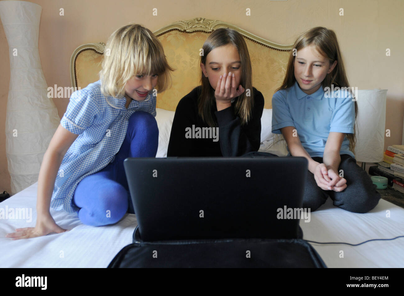 Three girls in school uniform using a laptop computer on their parents ...