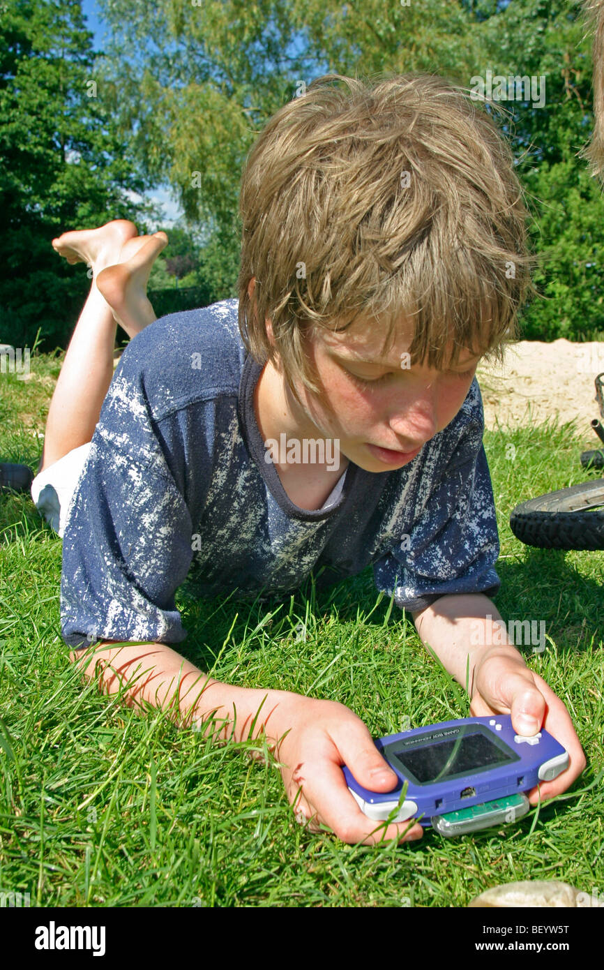 teenager playing game boy at a park Stock Photo - Alamy