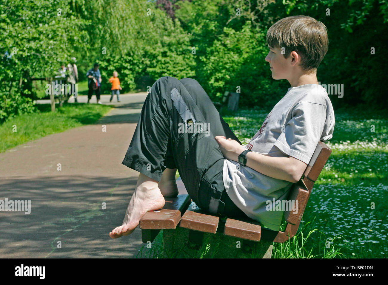 portrait of a teenage boy sitting on a bench in a park Stock Photo - Alamy