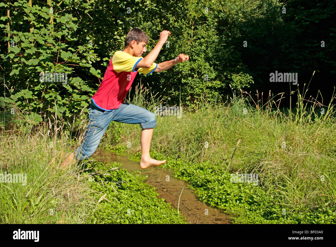 Boy jumping across water hi-res stock photography and images - Alamy
