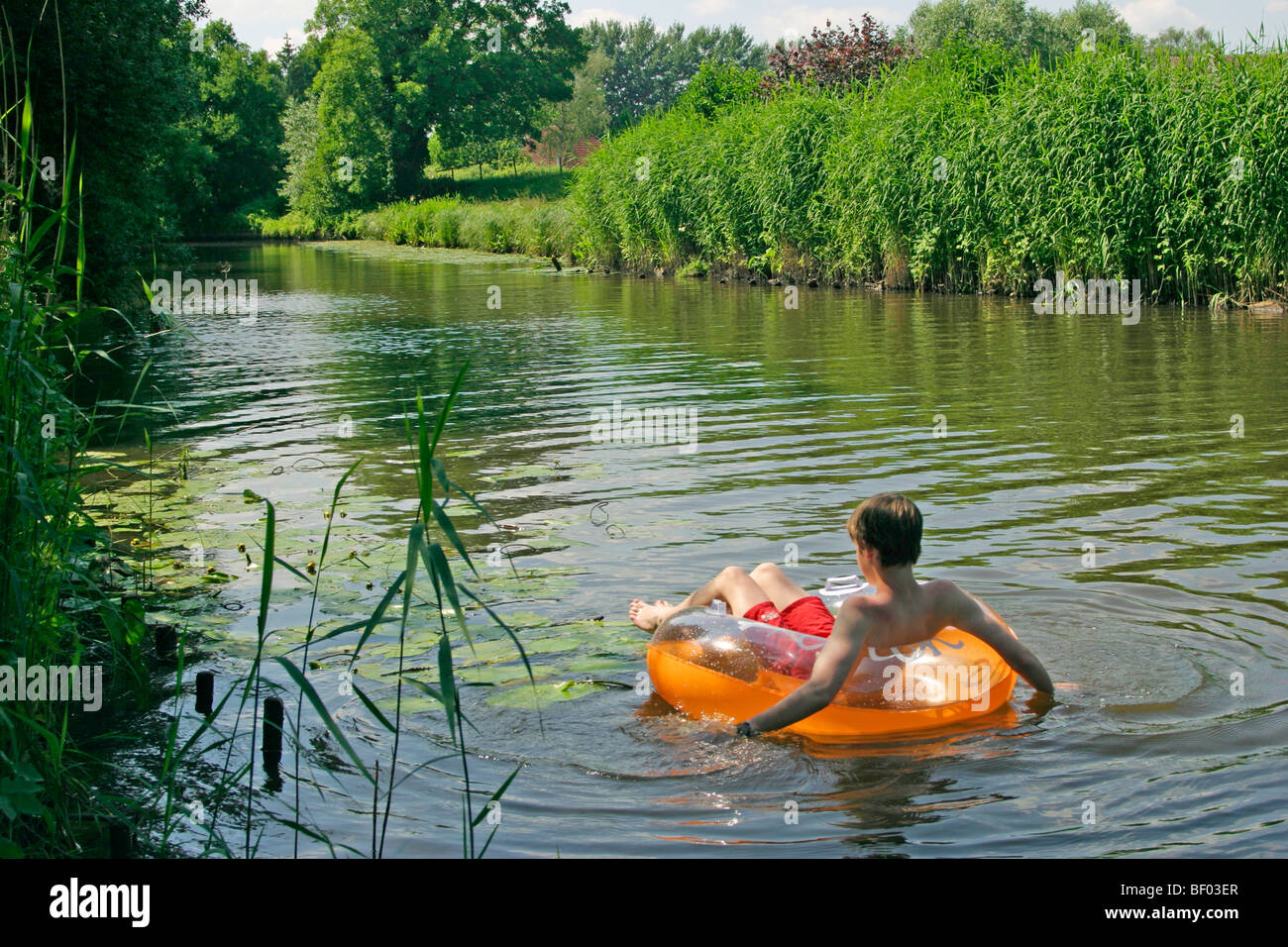 teenage boy in a rubber floating tire on a river Stock Photo - Alamy