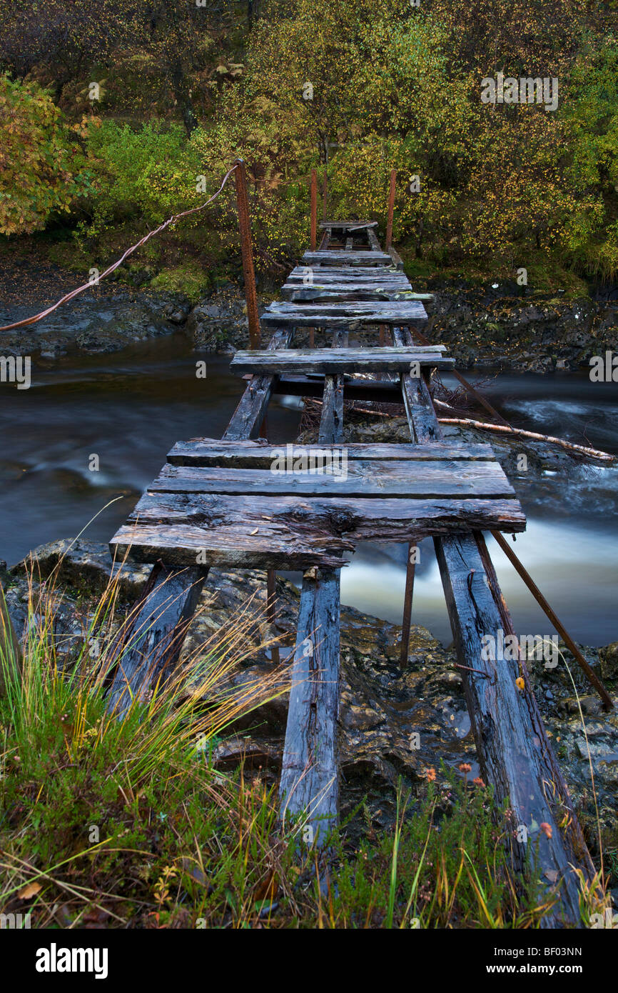 An old wooden footbridge crosses a river near Portree, Isle of Skye ...