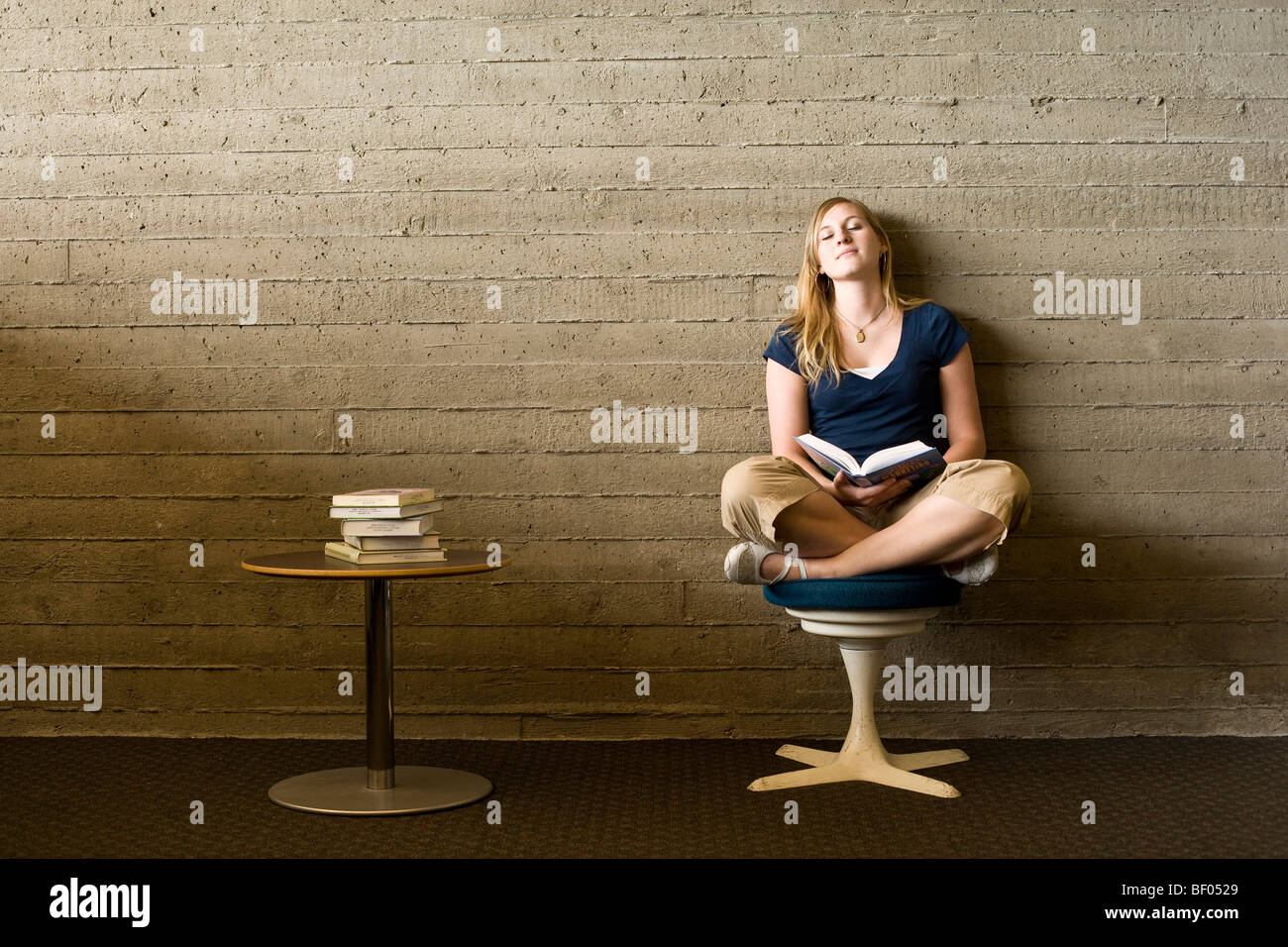 Young woman reading in a library Stock Photo - Alamy
