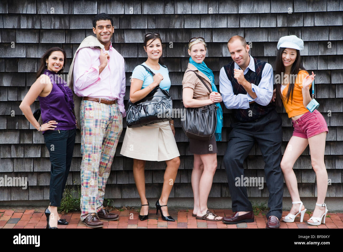 Friends standing in front of wall and smiling Stock Photo - Alamy
