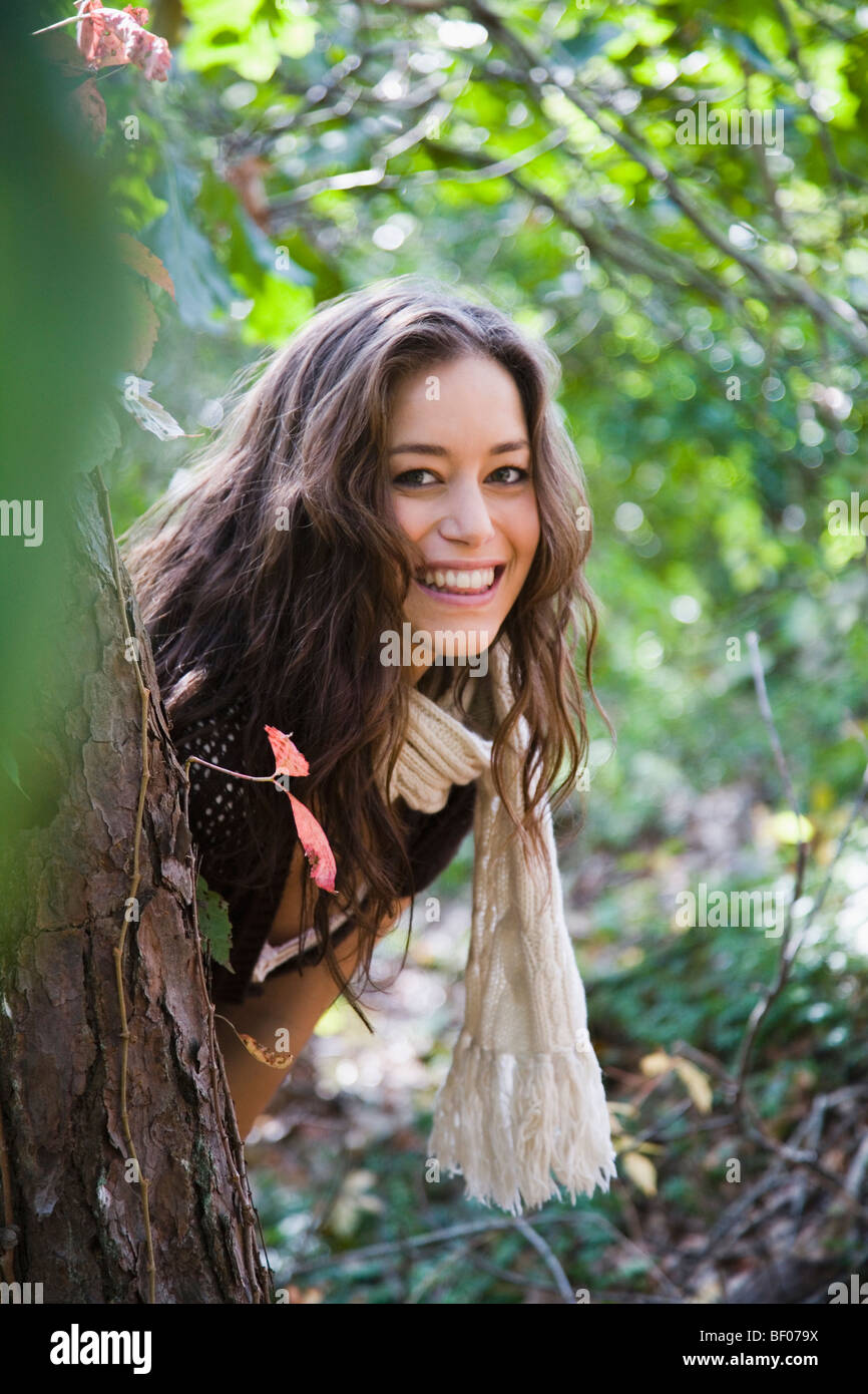 Woman looking behind a tree Stock Photo - Alamy