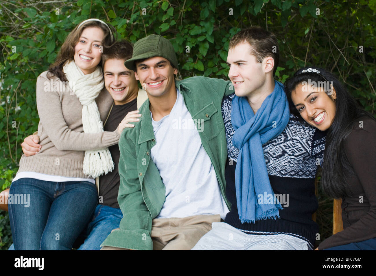 Group of friends sitting together and smiling Stock Photo - Alamy