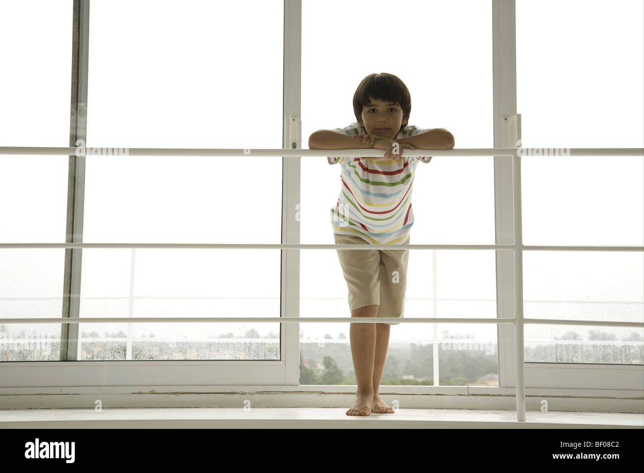 Boy leaning against a railing Stock Photo - Alamy