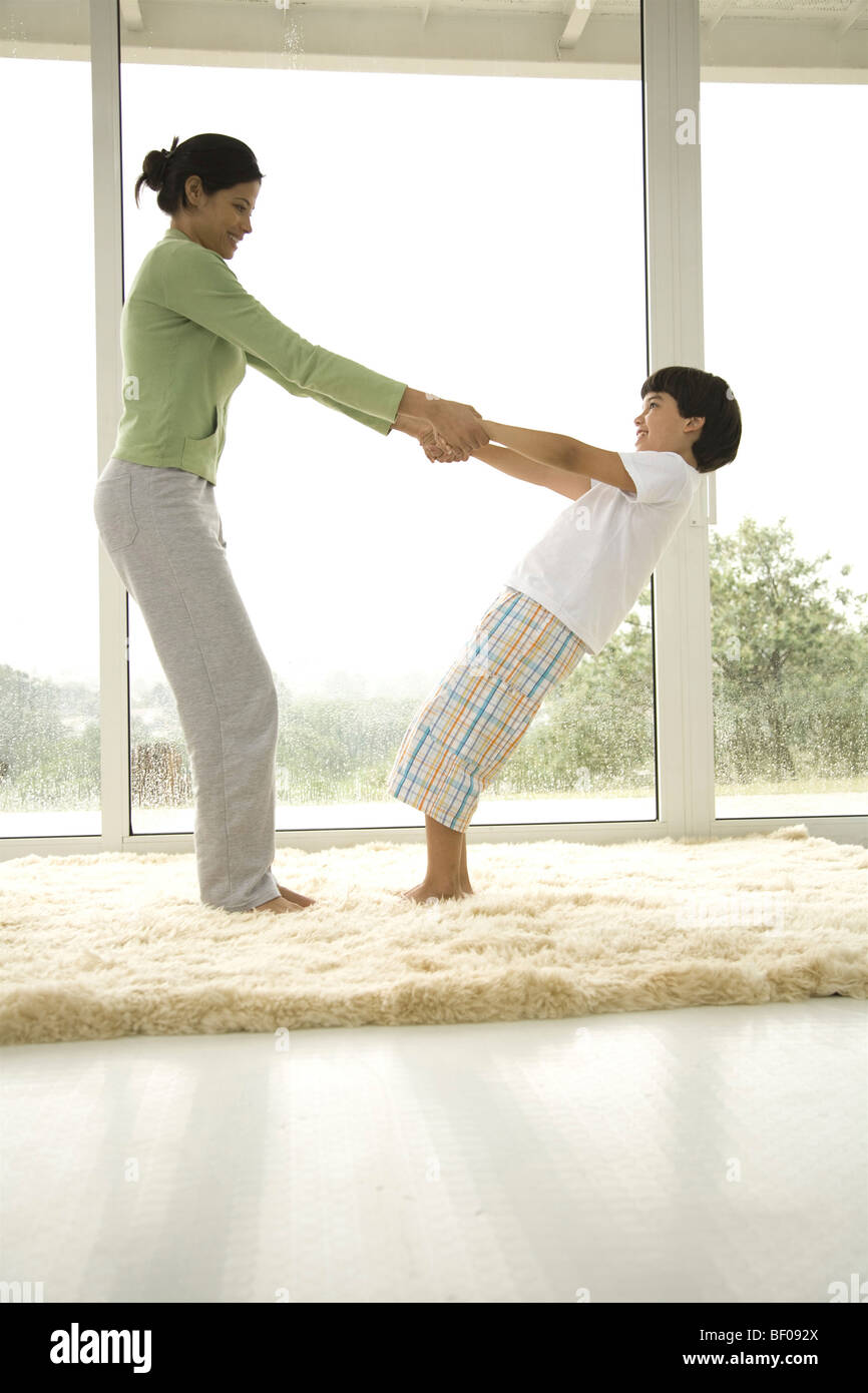 Side profile of a young woman playing ring-around-the-rosy with her son ...