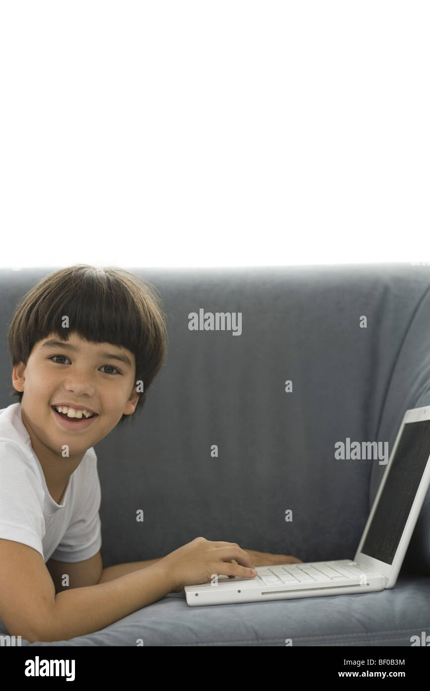 Boy lying on a couch and using a laptop Stock Photo - Alamy
