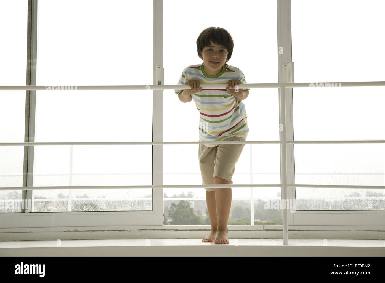 Boy leaning against a railing Stock Photo - Alamy