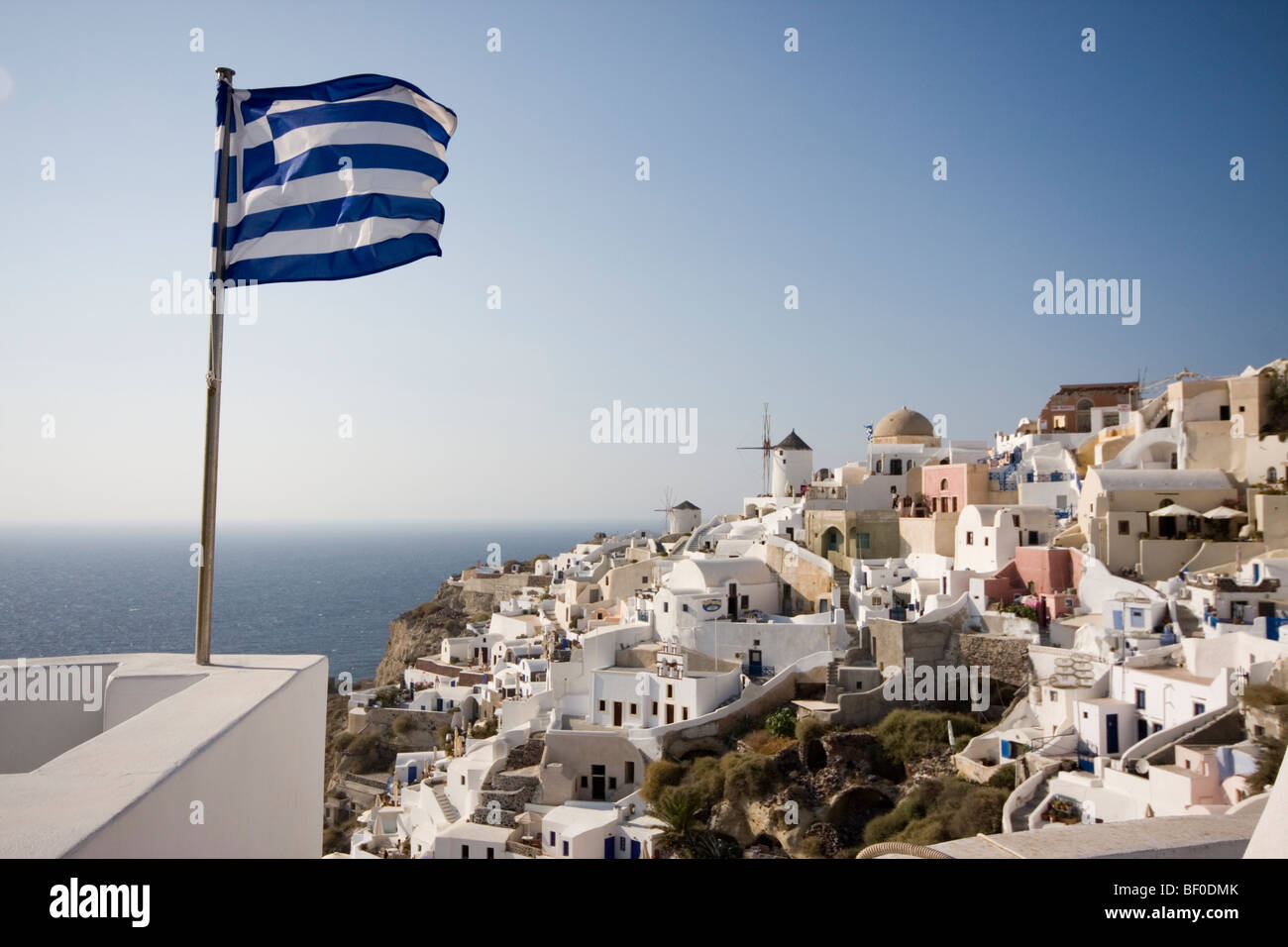 Greek flag hanging over Oia, Santorini buildings on hillside Stock ...