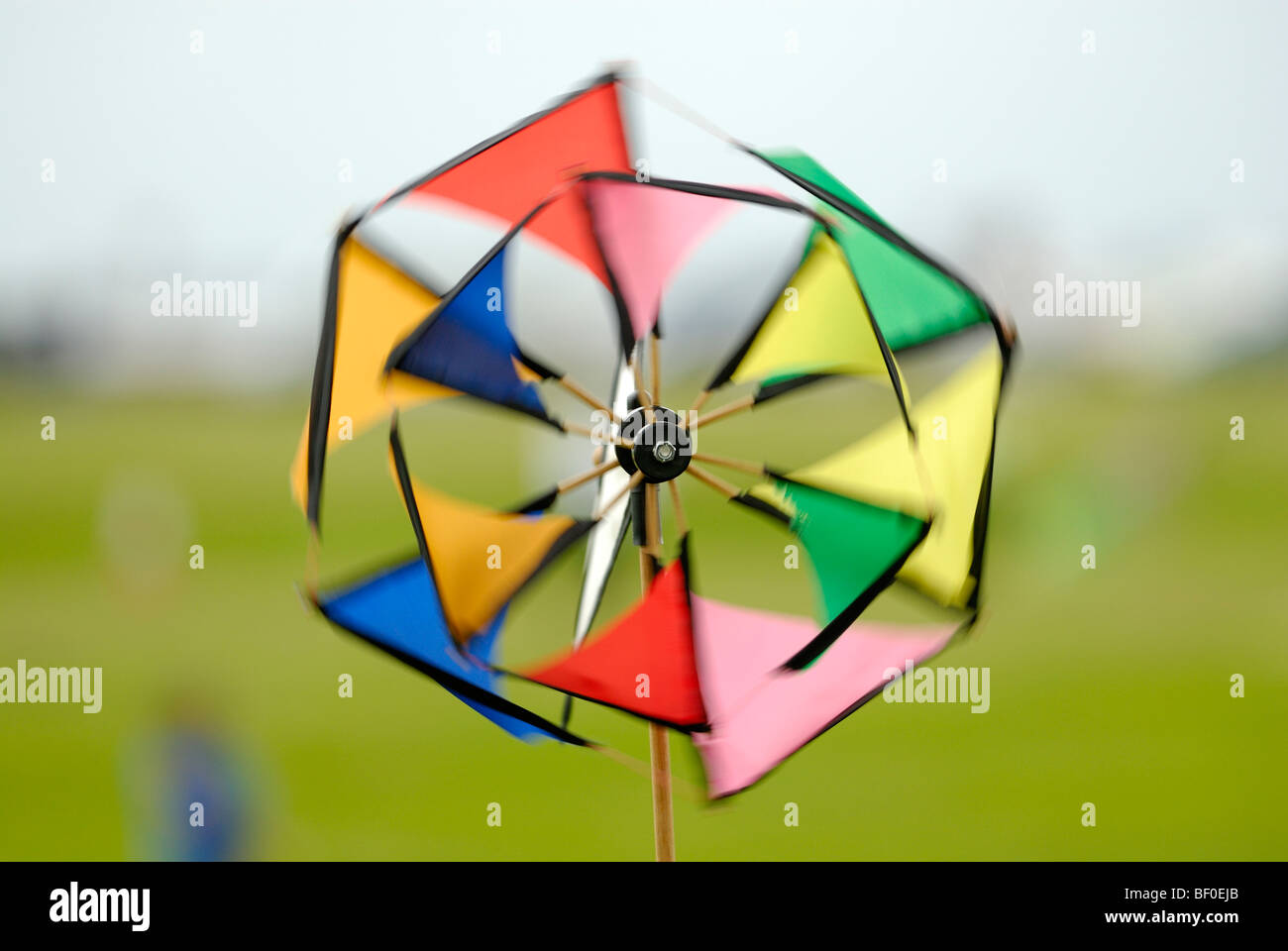 Colourful childs windmill being blown in wind Stock Photo - Alamy