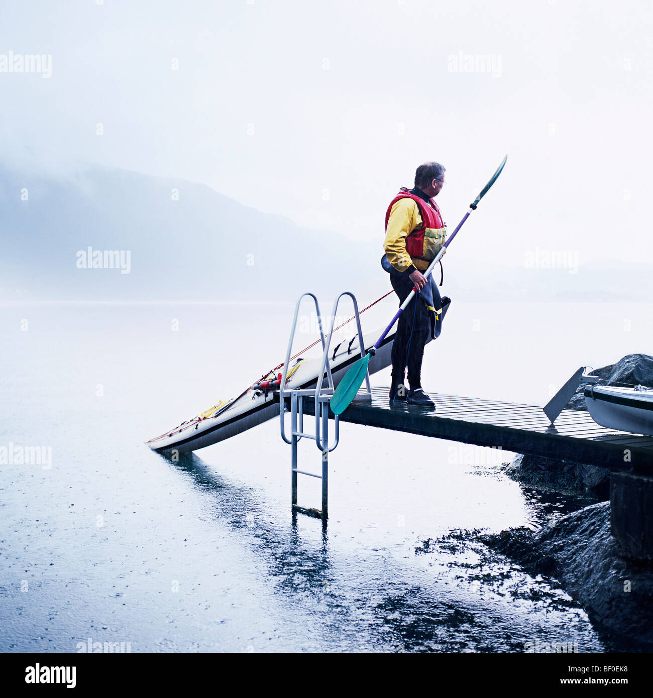 Man pulling kayak onto dock Stock Photo - Alamy