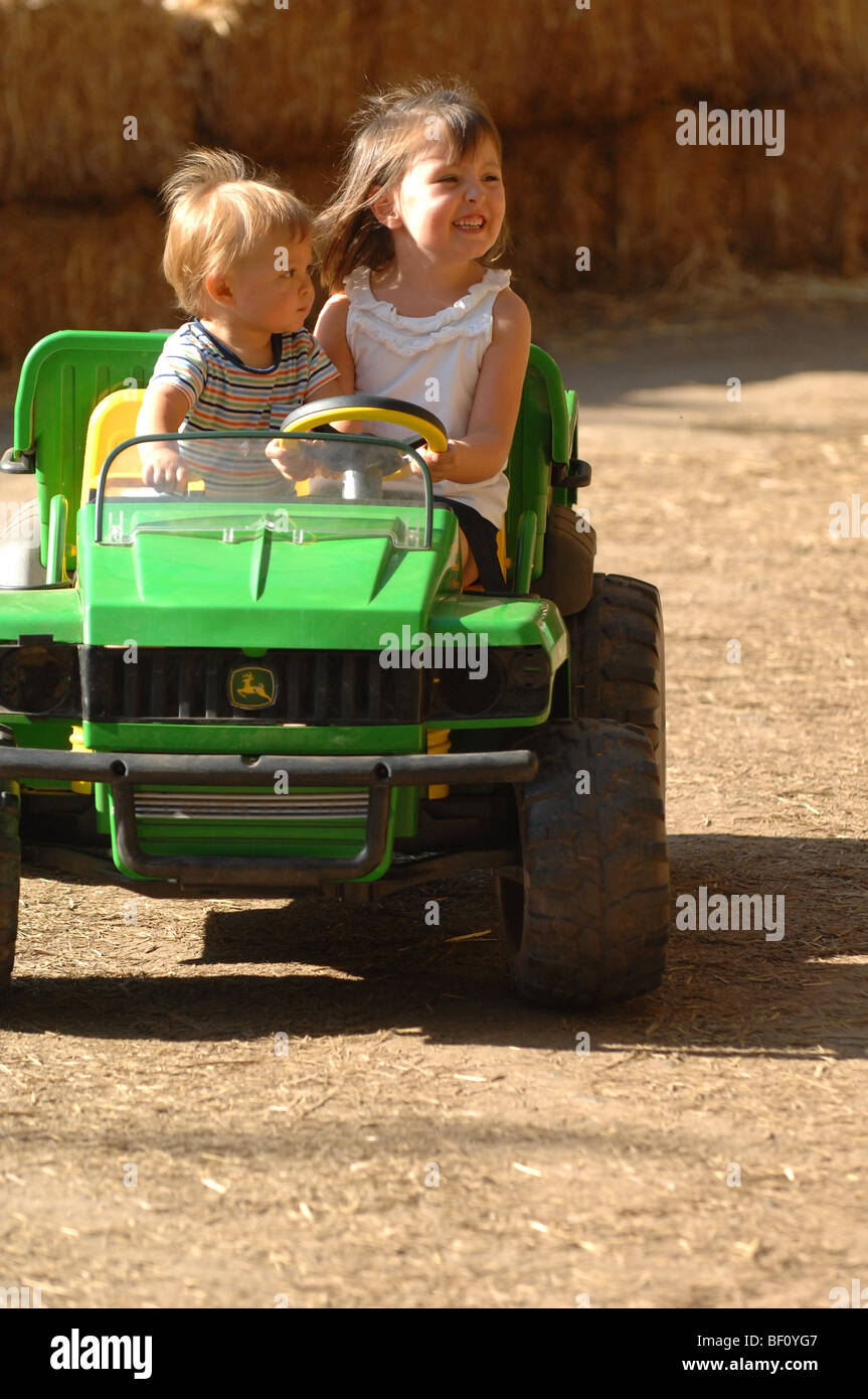 Young children enjoy driving toy-tractors at on a makeshift tractor ...
