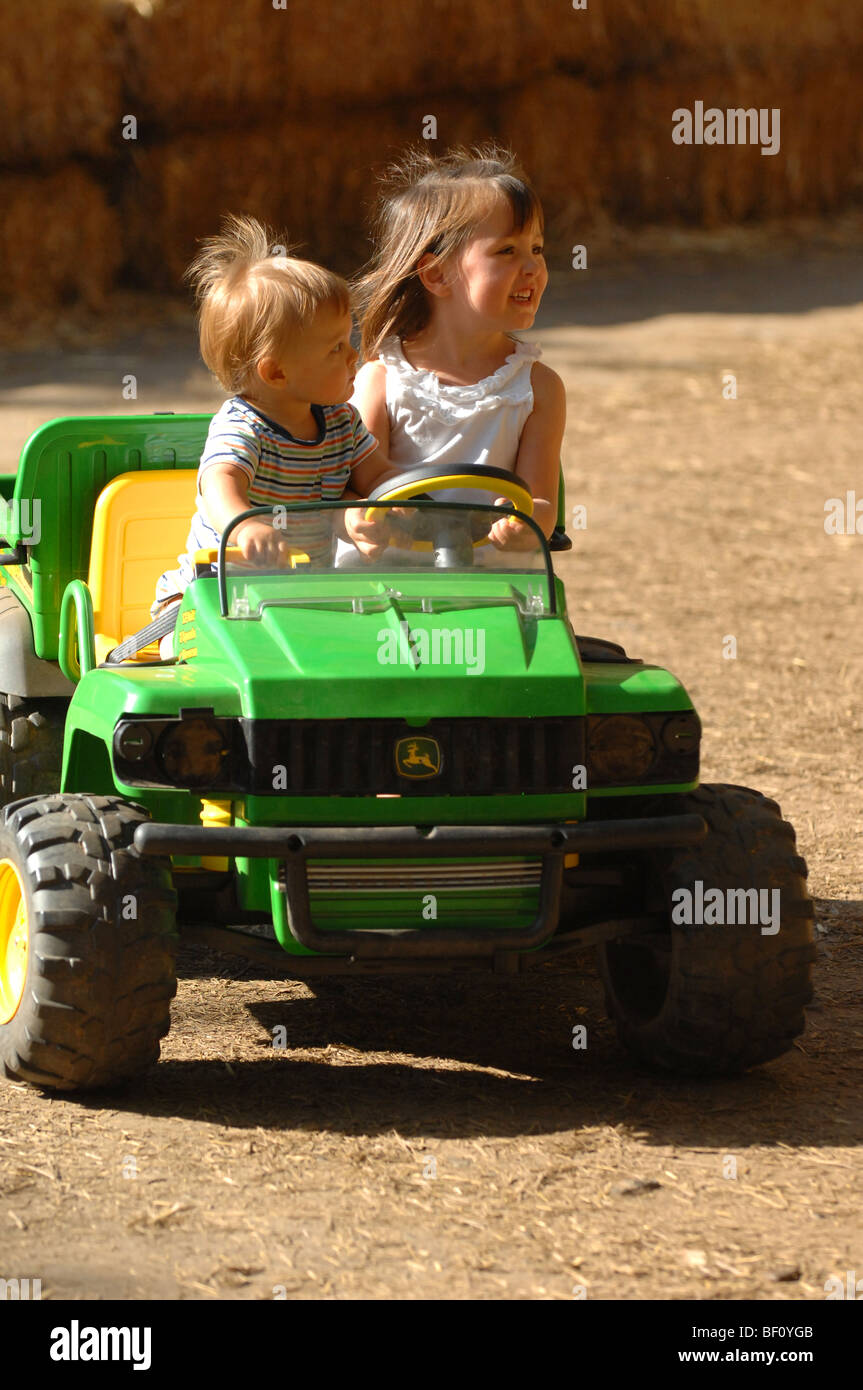 Young children enjoy driving toy-tractors at on a makeshift tractor ...