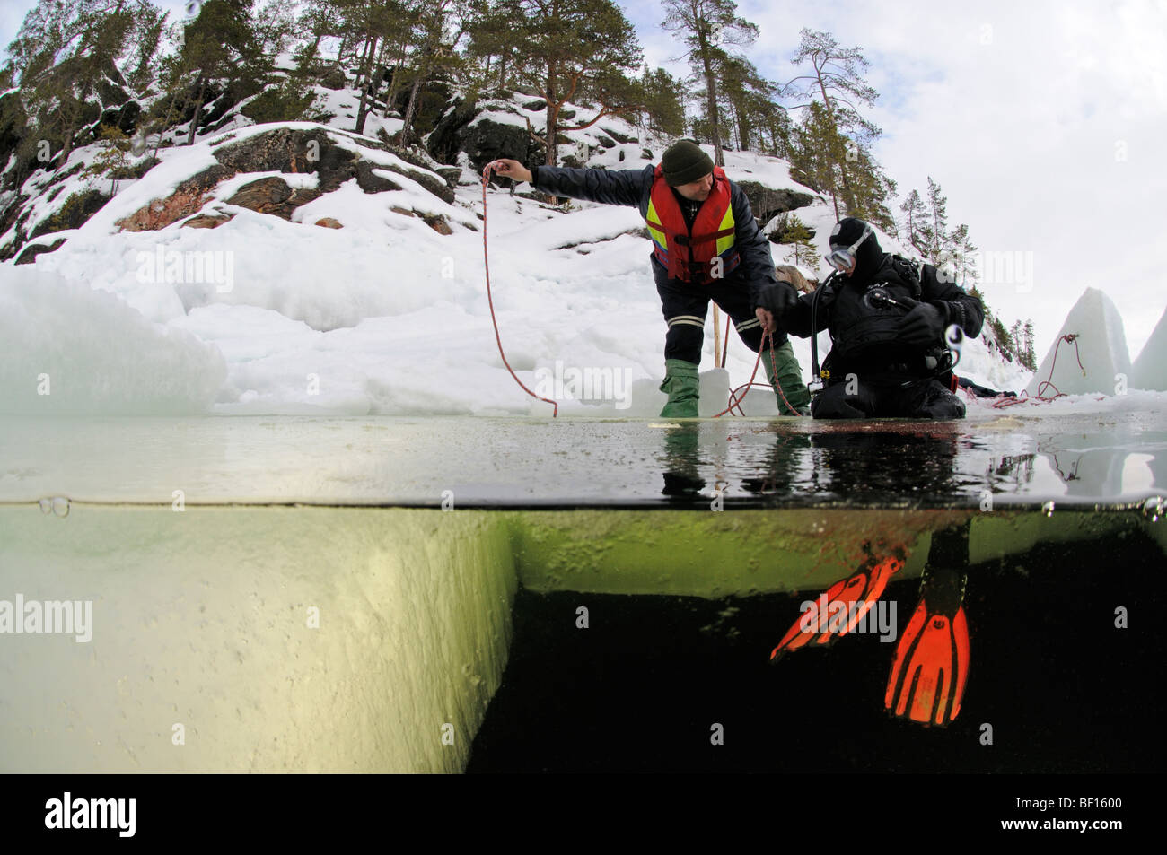 split shot from ice diving, ice diver sitting on the ice hole, White ...