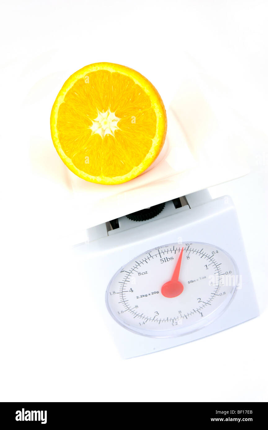 A sliced orange on top of a set of kitchen scales isolated against a ...