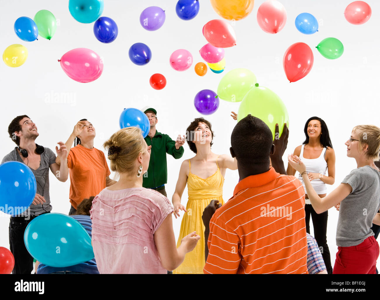 A group of men and women reaching for floating balloons Stock Photo - Alamy