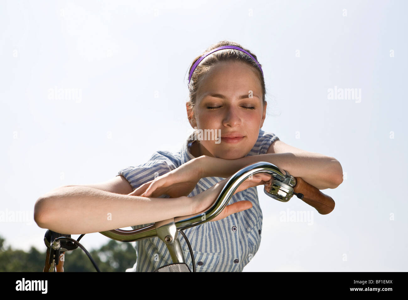 A young woman leaning on bicycle handlebars Stock Photo - Alamy