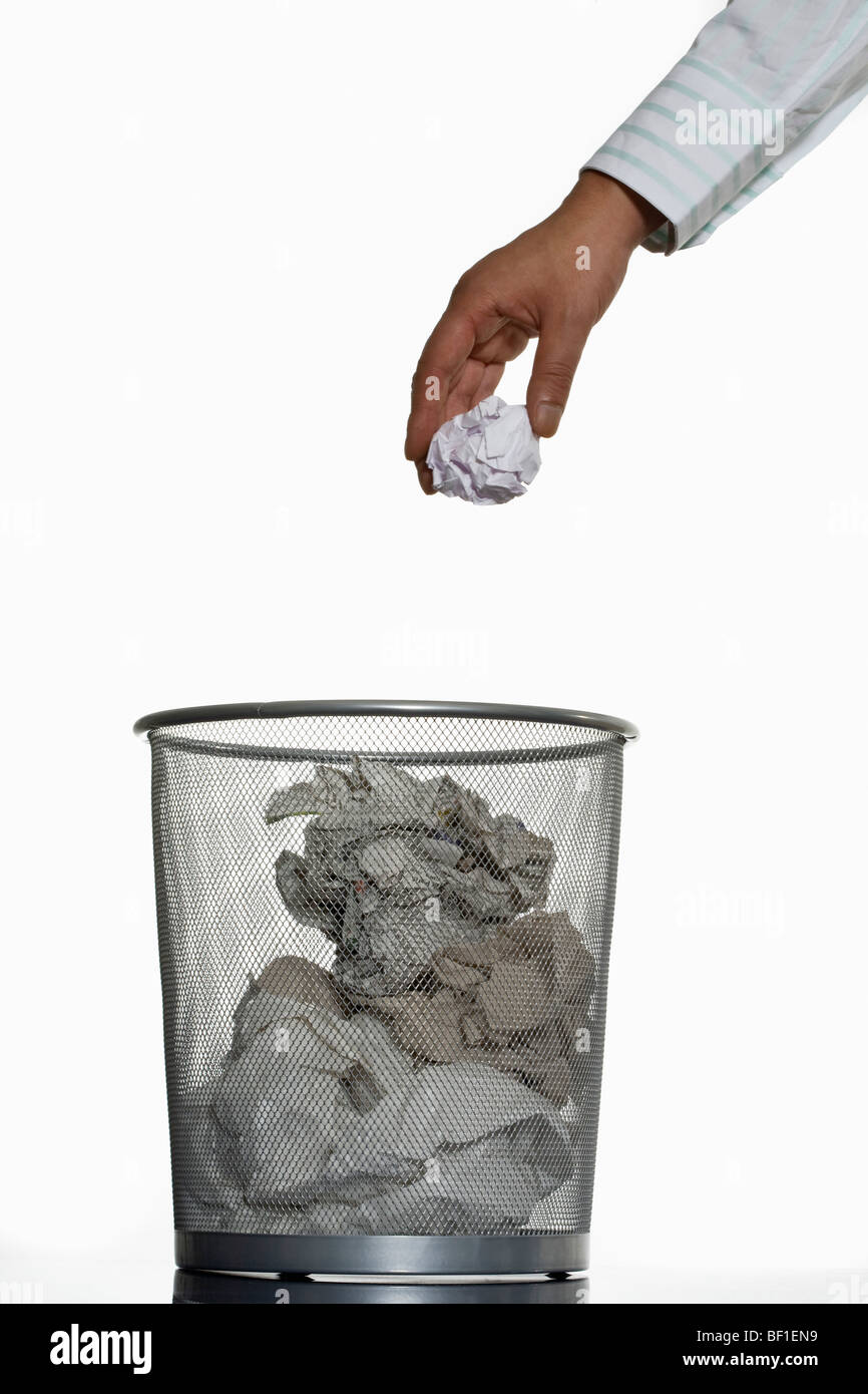 A human hand throwing a crumpled piece of paper into a wastepaper ...