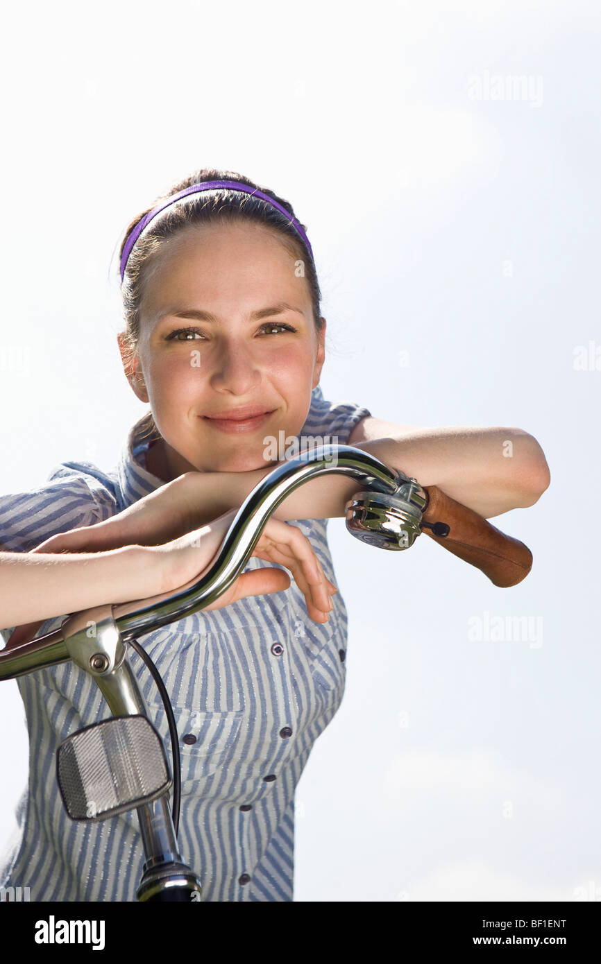 A young woman leaning on bicycle handlebars Stock Photo - Alamy