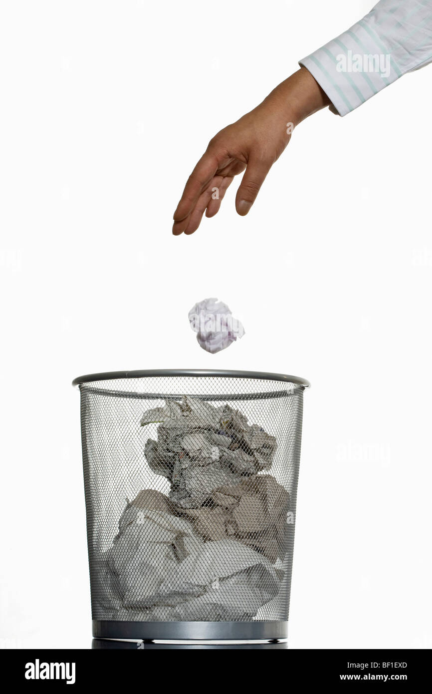 A human hand throwing a crumpled piece of paper into a wastepaper ...