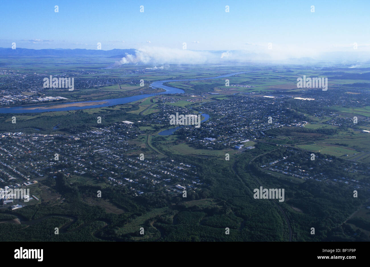 Aerial view over Mackay with forest fire behind, coastal region ...