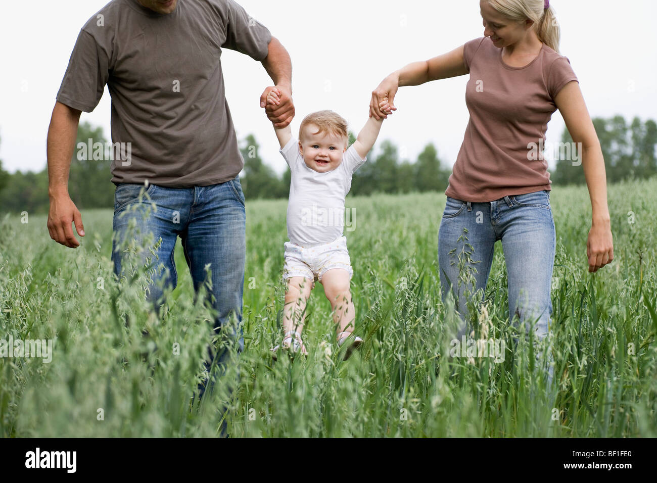 Two parents lifting a child in the air Stock Photo - Alamy